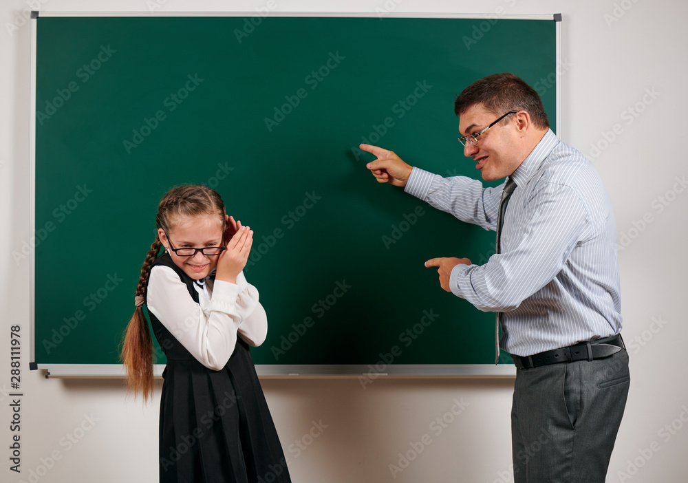 angry teacher shout to schoolgirl, posing at blackboard background ...
