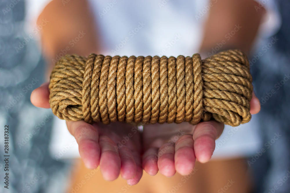 Women's hands holding a skeleton of jute rope in their gesture. The ...