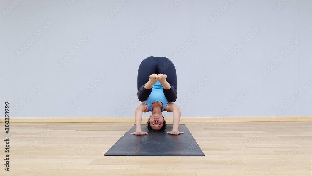 Young attractive woman practicing yoga standing in salamba sirsasana ...