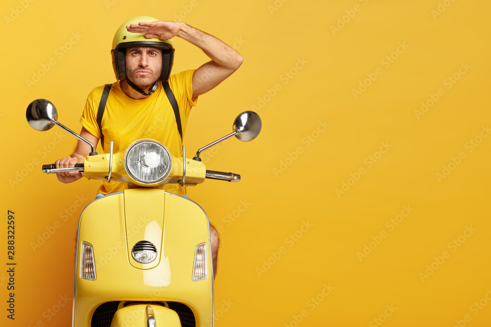 Concentrated male driver in helmet on scooter, keeps palm near forehead ...