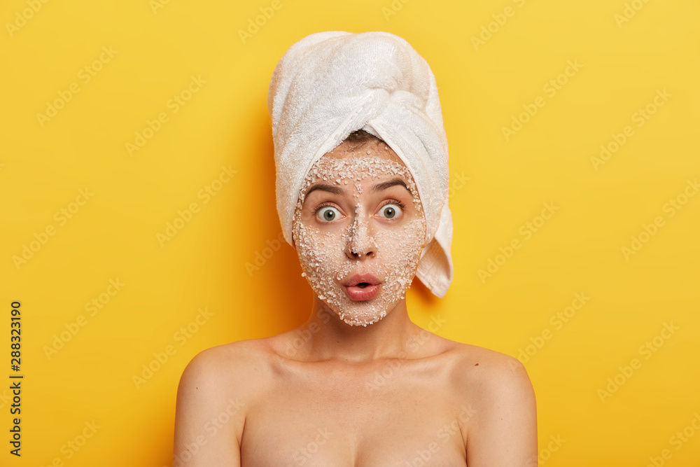 Stupefied young woman applies natural sea salt mask, reduces acnes and ...