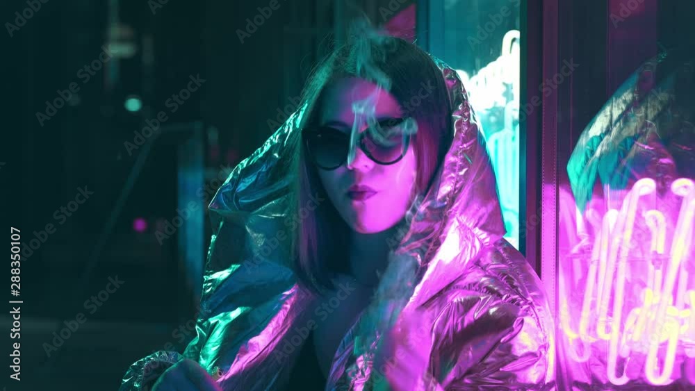 Millennial cool modern pretty girl smoking cigarette near glowing neon ...