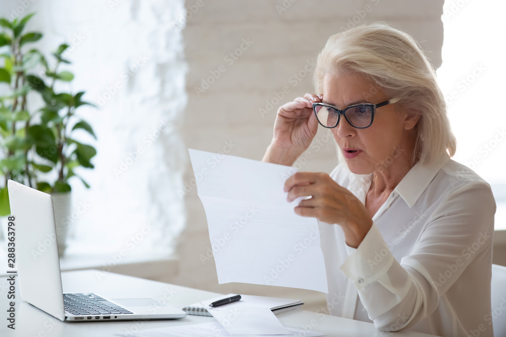 Confused senior businesswoman surprised reading paper letter Stock ...