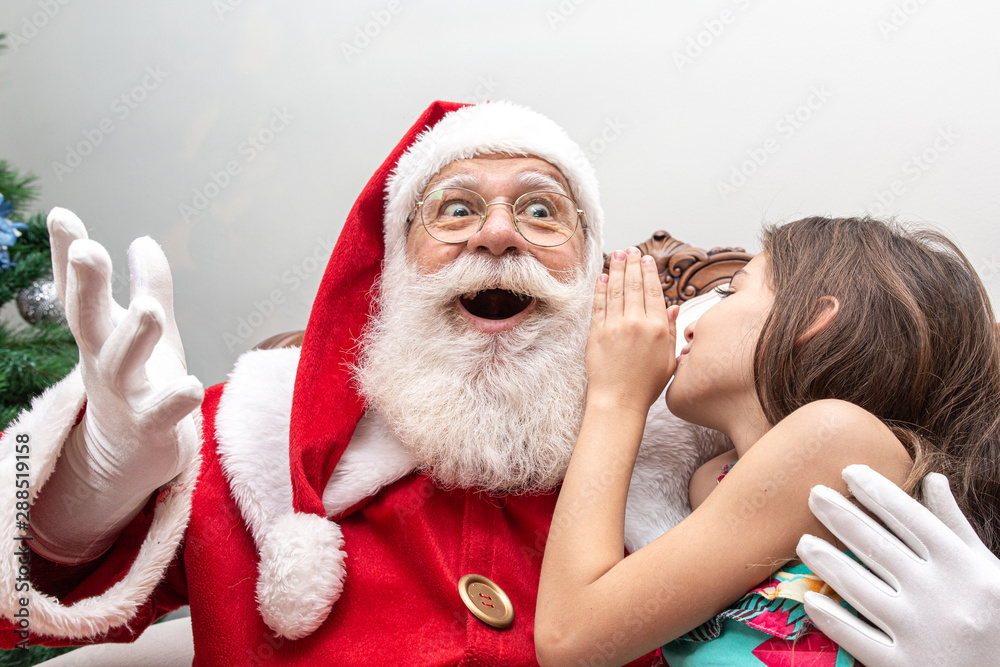 Little girl whispering in Santa's ear. Telling a secret. Revealing the ...