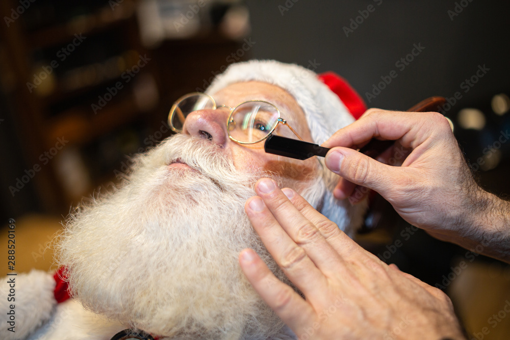 Foto de Santa Claus shaving in barbershop. Looking in the mirror ...