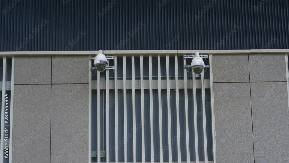 Two new cameras are hanging on a modern building. metal tile lattice ...