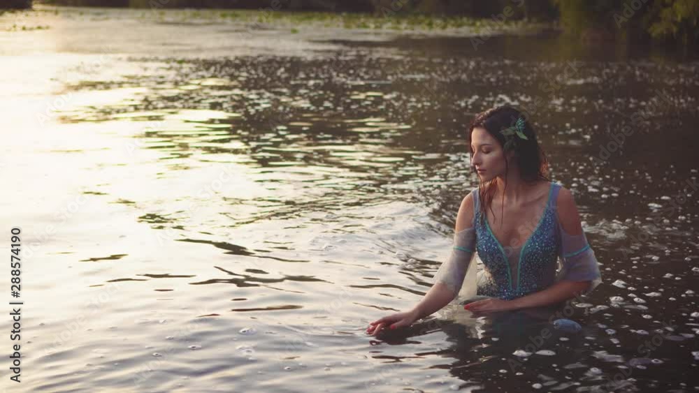 Woman brunette goddess with wet hair in a elegant evening blue dress is ...