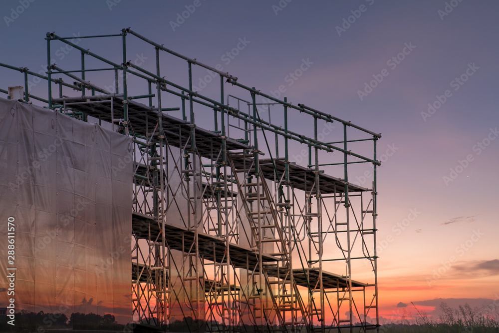 Construction site with scaffold tower and building with sunset ...