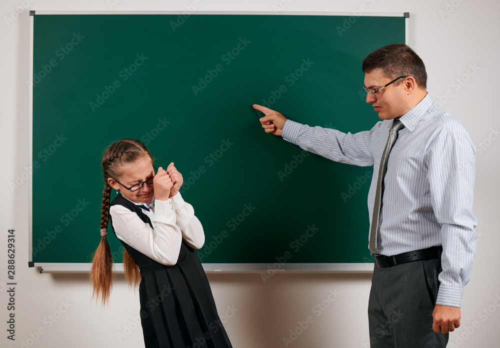 angry teacher shout to schoolgirl, posing at blackboard background ...