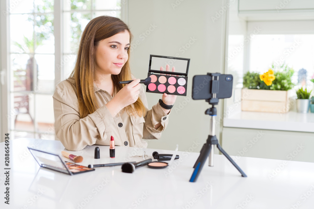 Beautiful young influencer woman recording make up video tutorial with ...