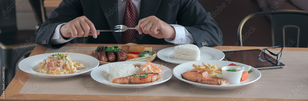 Man eating lots of food on the table with fired fish, pork steak, steam ...