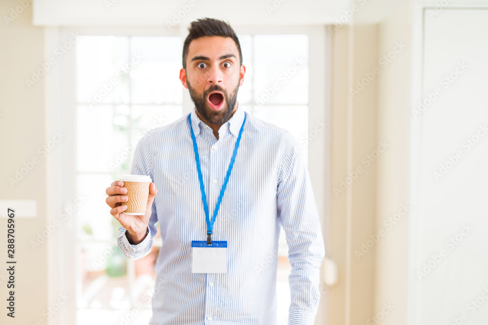 Handsome hispanic man wearing id card and drinking a cup of coffee ...