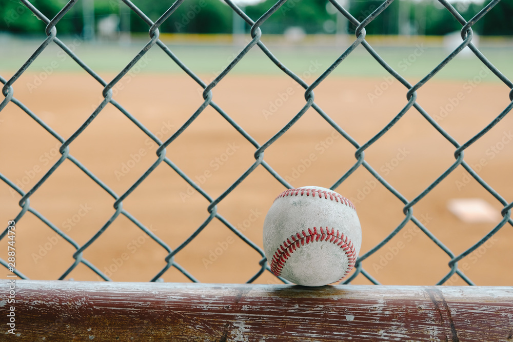 Baseball close up with chain link fence and ball field in background ...
