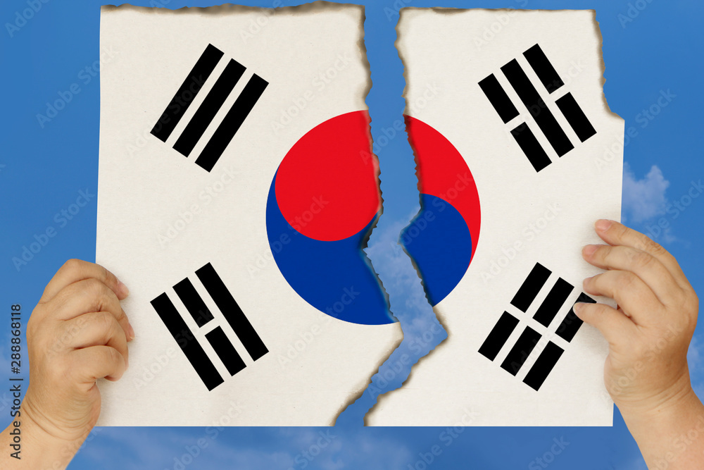 woman holds in both hands against a blue sky torn in two cardboard with ...