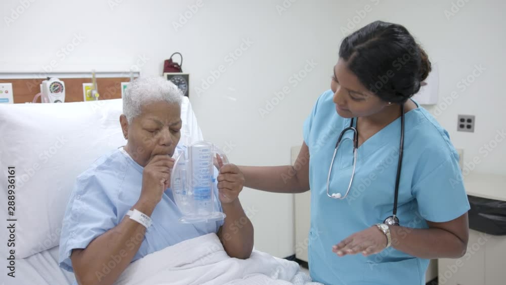 Nurse helps female patient with spirometer in hospital patient room ...