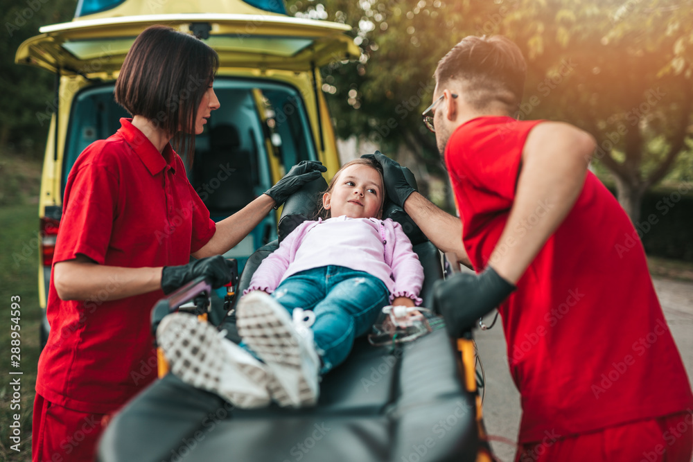 Foto de Doctors with injured little girl in front of ambulance car. do ...