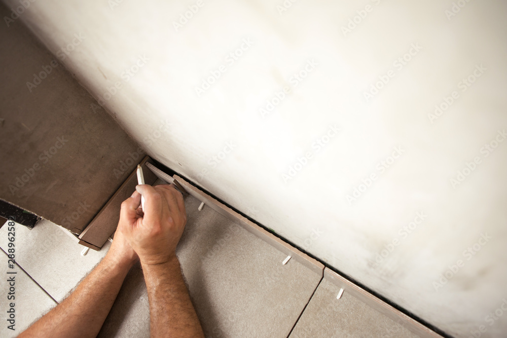 Hands of a construction worker marking where to place a ceramic tile ...