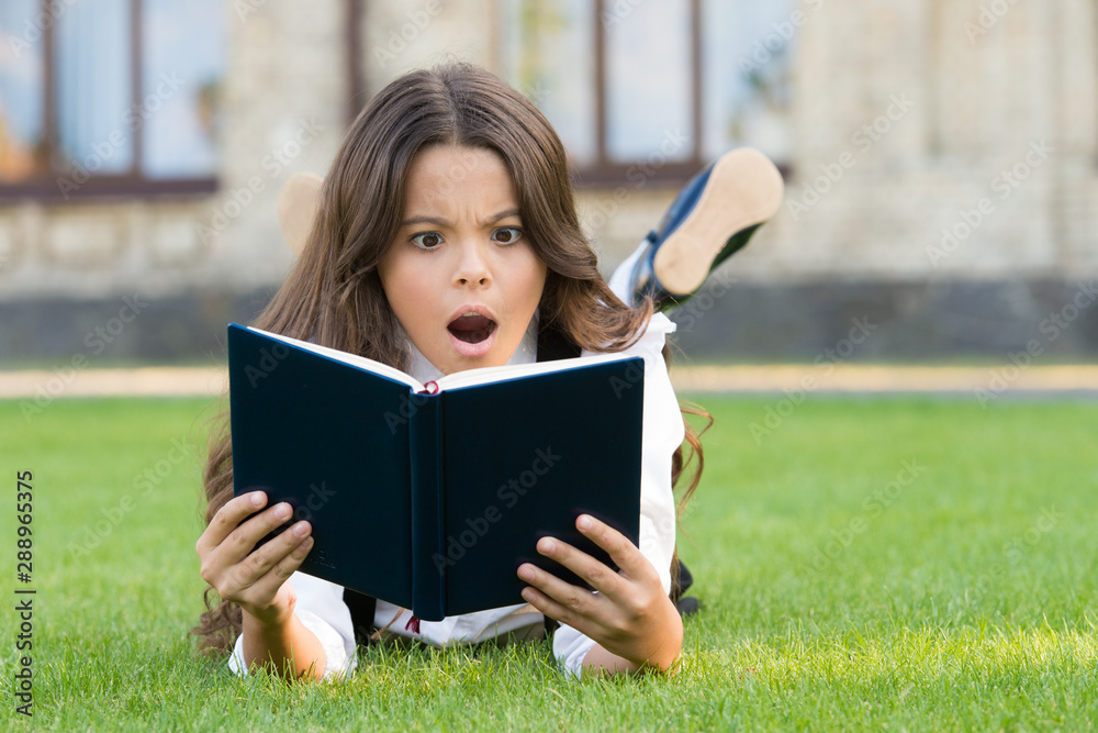 Extracurricular reading. Cute small child reading book outdoors. Basic ...