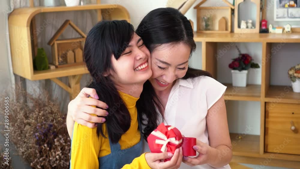 Asian middle-aged mother touching Smiling happy Asian teenage daughter in indoor living room at ...