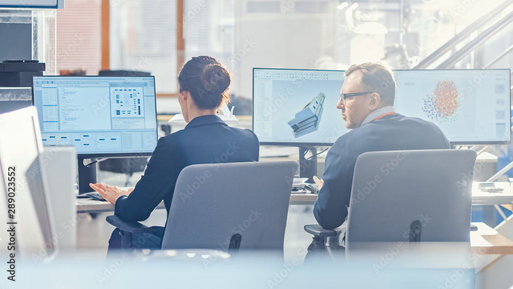 Back View of Team of Technology Engineers Working on Desktop Computers in Office. Screens Show ...