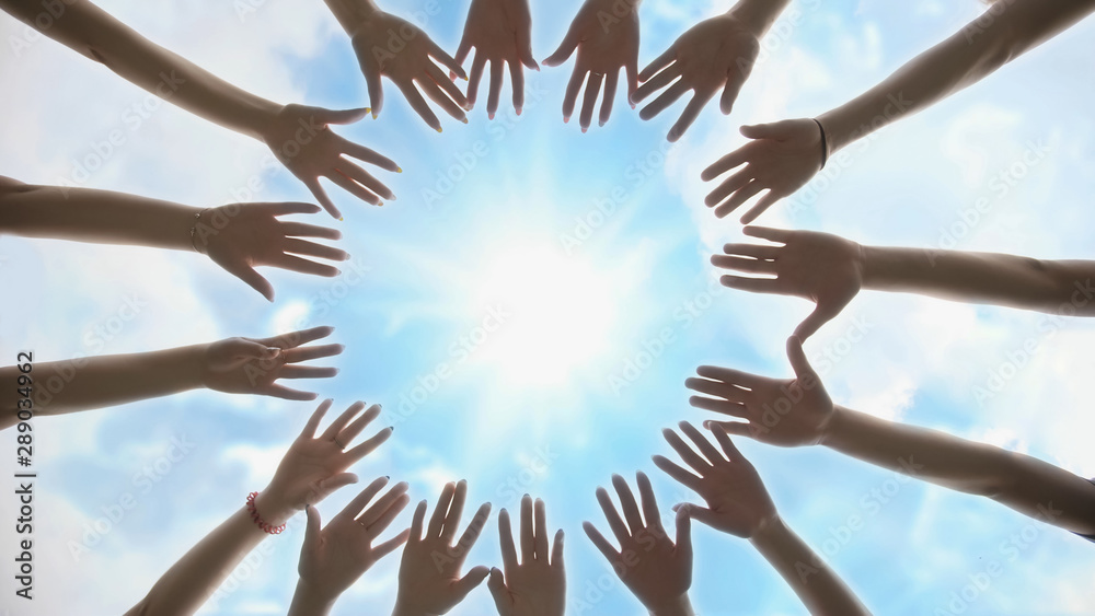 A group of young people make a circle out of their hands. Diverse ...