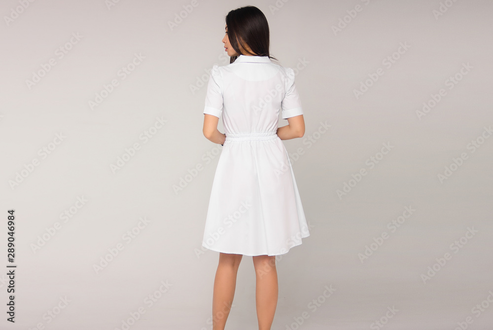 young stylish brunette nurse in white medical dress is standing from ...