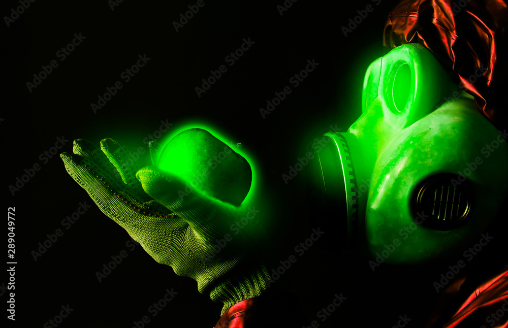 Man in the gas mask holding radioactive luminous apple. Radiation ...