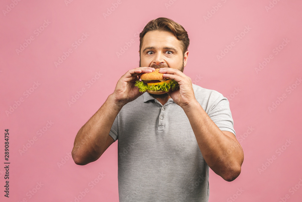 Young man holding a piece of hamburger. Bearded gyu eats fast food ...