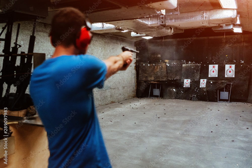 firing pistol at target in indoor shooting range Stock Photo | Adobe Stock