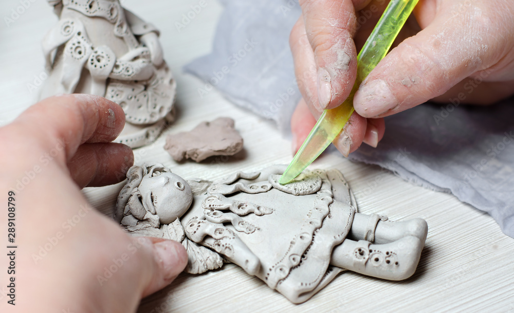 The process of making a souvenir doll made of clay. Female hands ...