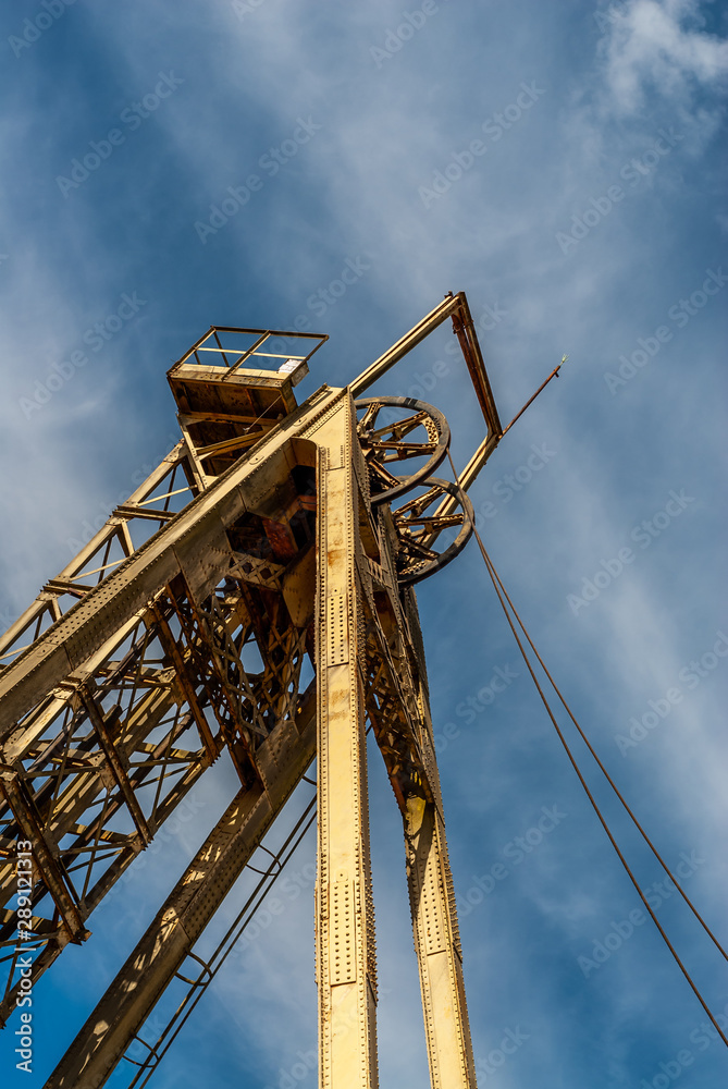 Mining old equipment. Shaft head frame in steel, detail of the wheels ...
