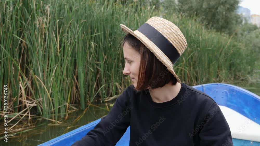 Young caucasian girl in straw hat rowing on boat and smiling. Happy ...