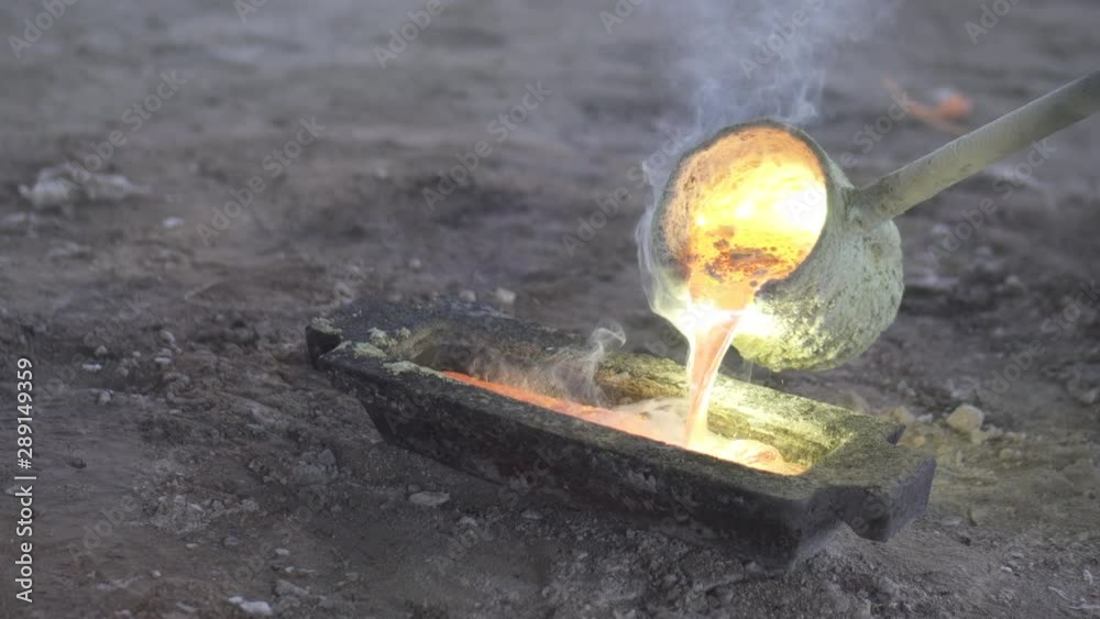 Artisan working gold melting process. Molted metal pouring into bar ...