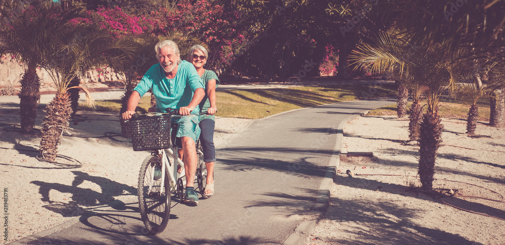 Foto de beautiful couple of seniors riding a tandem together having fun ...