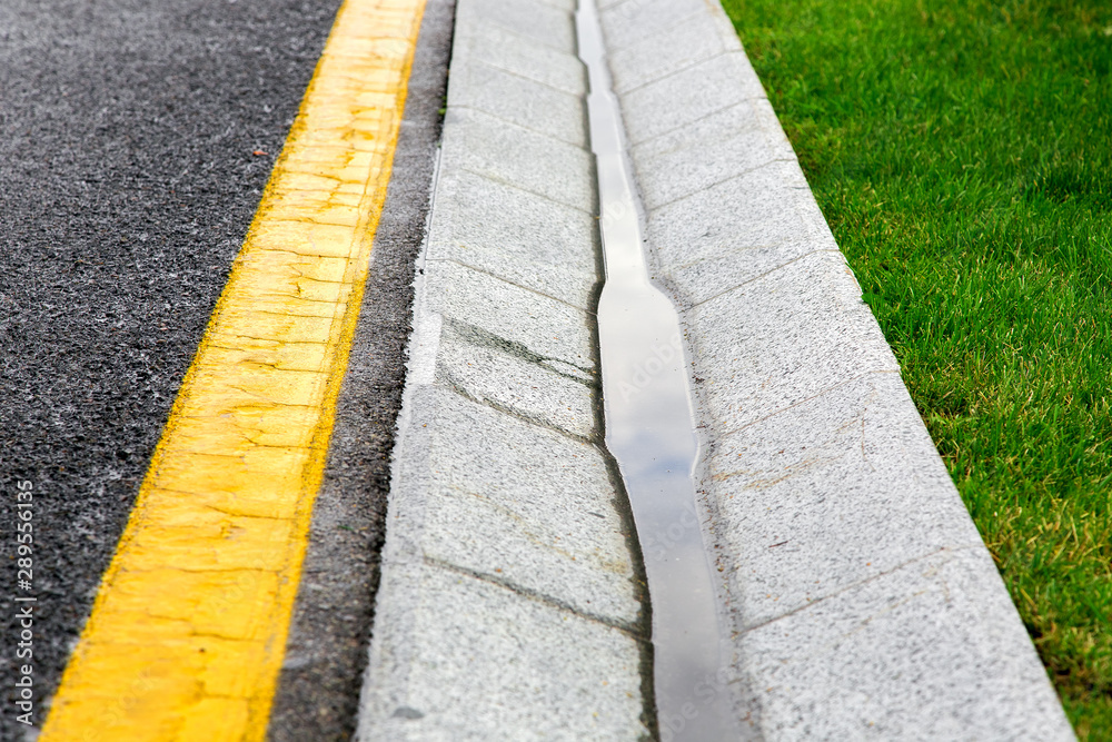 storm water channel concrete gutter with rain water on the side of a ...