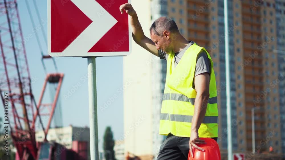 A tired worker at a construction site is upset after hard work and is ...