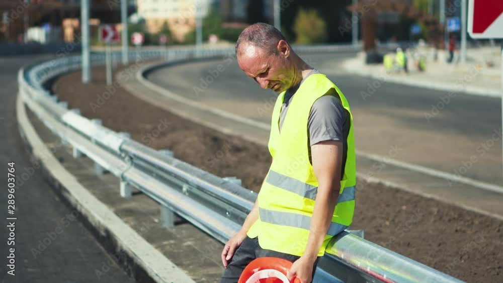 A tired worker at a construction site is upset after hard work and is ...