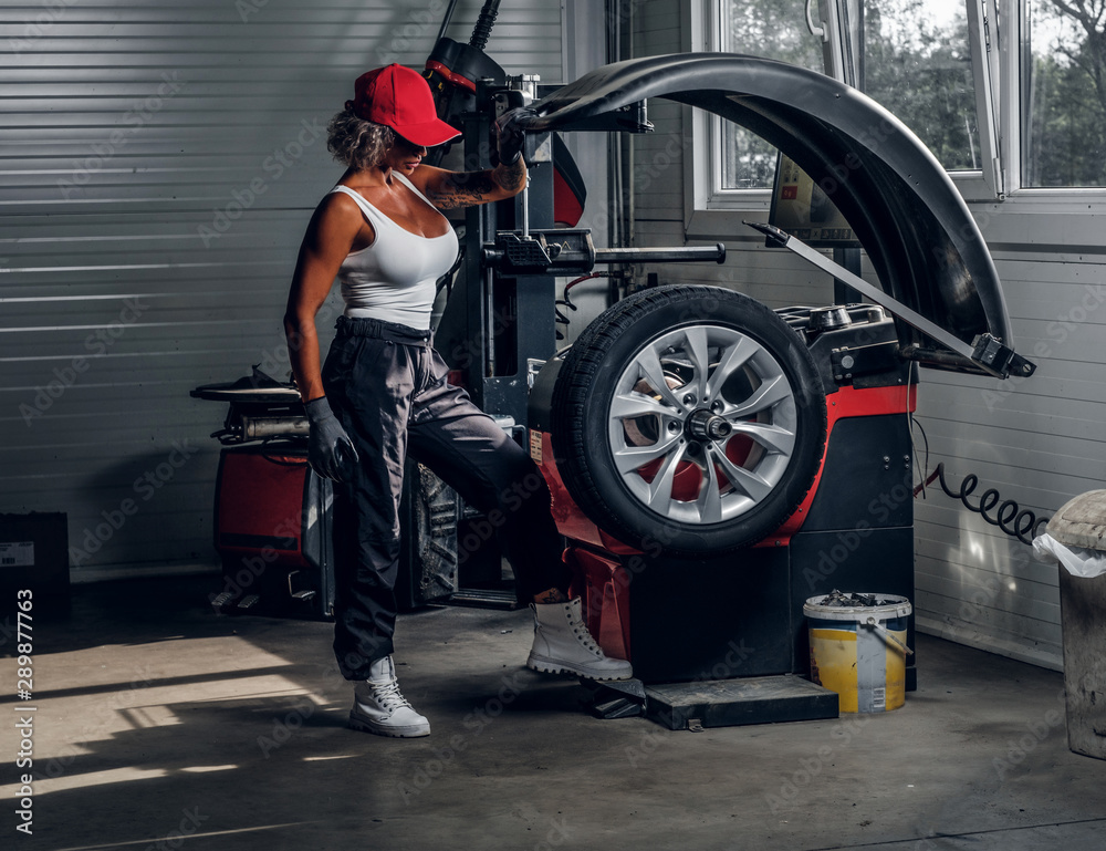 Professional female auto mechanic is fixing broken car at auto workshop ...