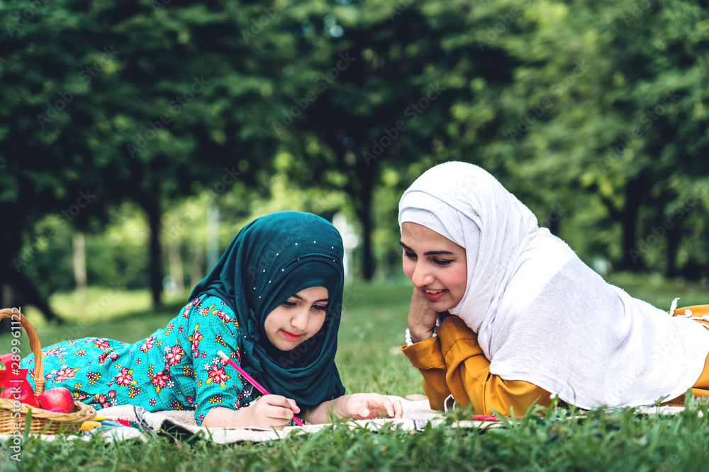 Portrait of happy muslim mother and little muslim girls child learning ...
