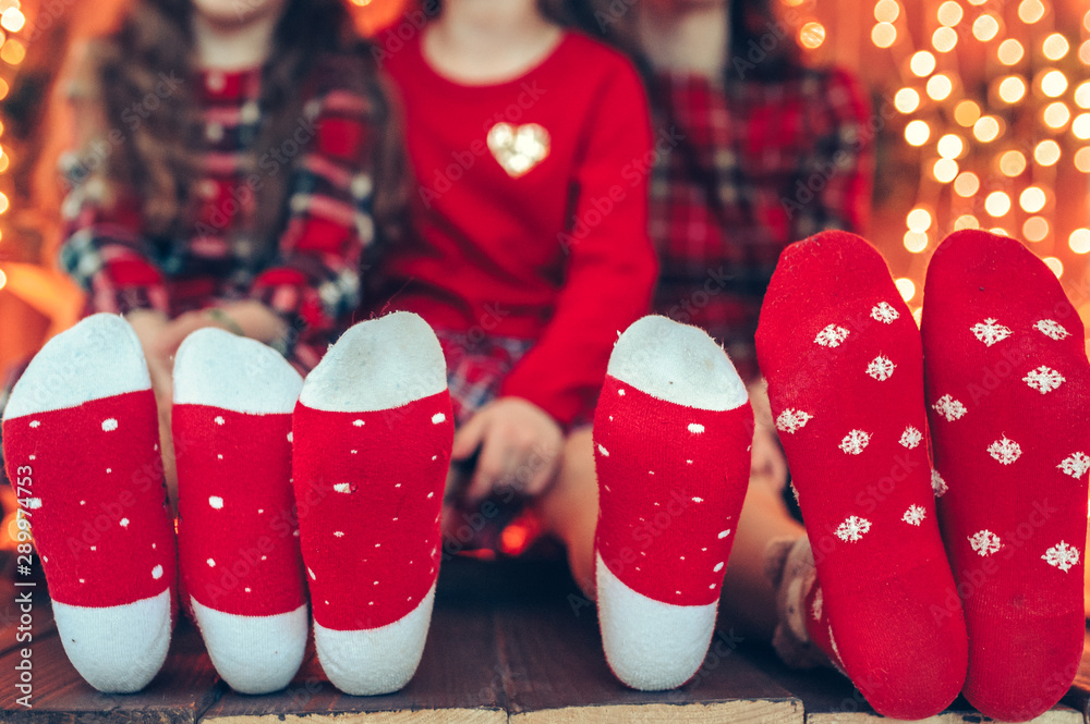 Feet wearing Christmas socks on wood floor. Happy family of three girls ...