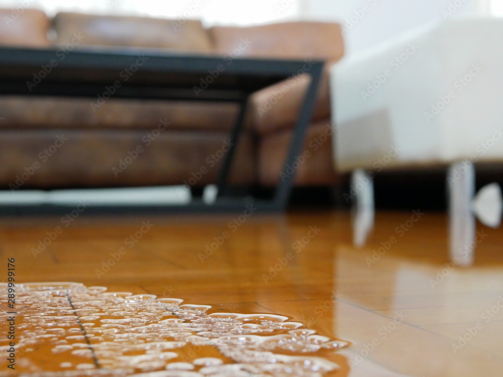 Close up of water flooding on living room parquet floor in a house ...