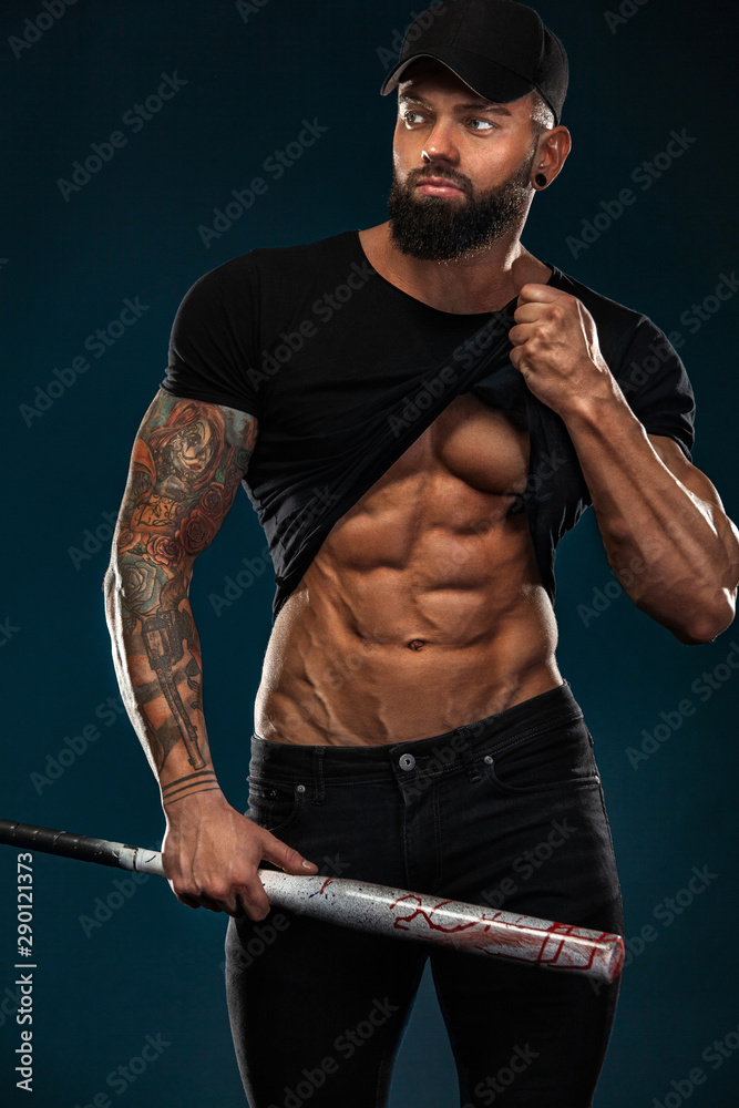 Strong and fit man bodybuilder with baseball bat shows abdominal ...