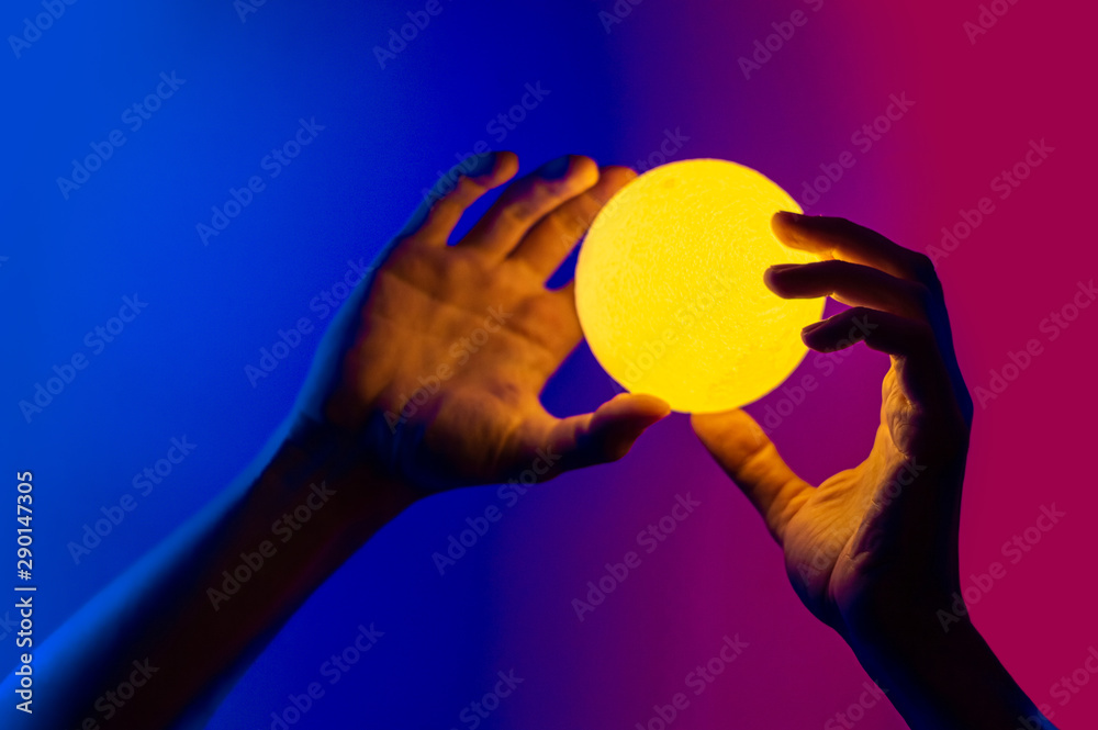 Man holding yellow moon shape illuminated sphere. Surrealistic photo ...