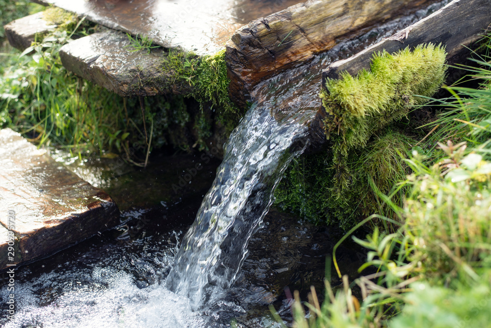 Water from a natural spring flows through a wooden gutter. Stock Photo ...