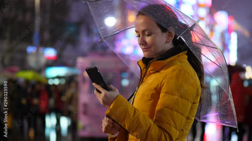 Tourist woman stay with umbrella under light rain, stare to phone ...