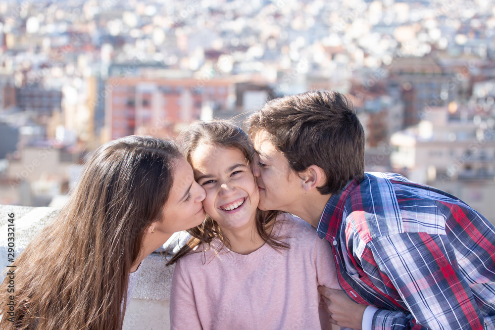 Dos hermanos besando a la vez a su hermana pequeña en la azotea Stock ...