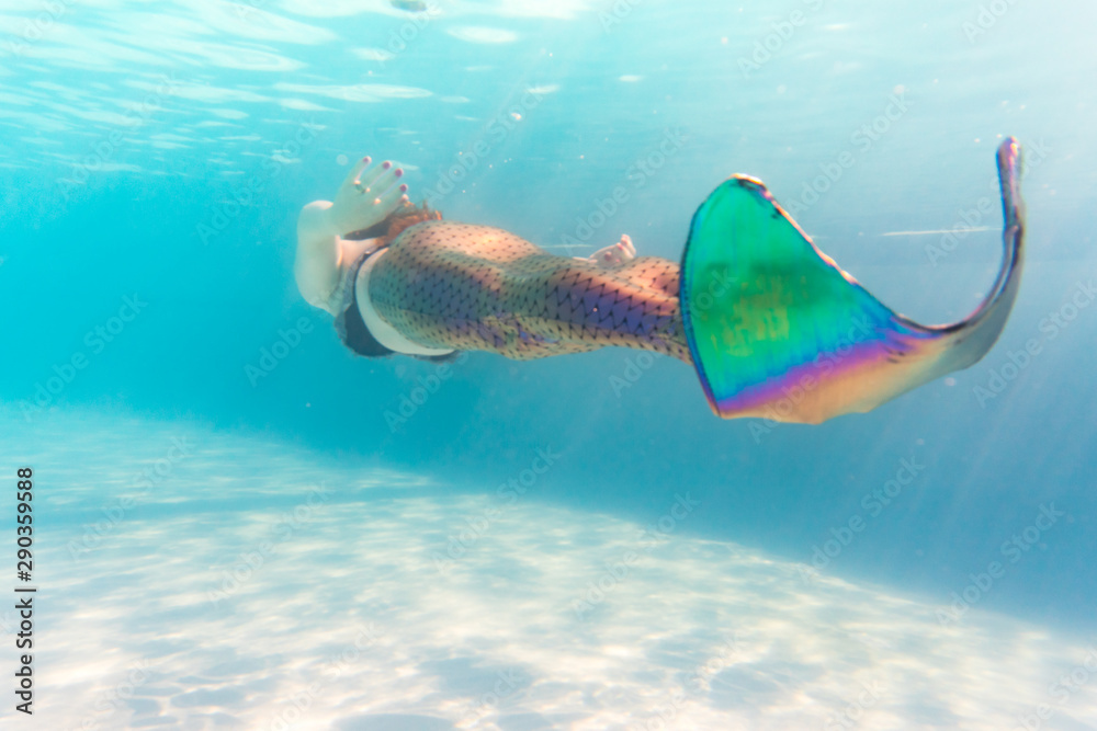 Woman on vacation gracefully swimming in pool wearing colorful mermaid ...