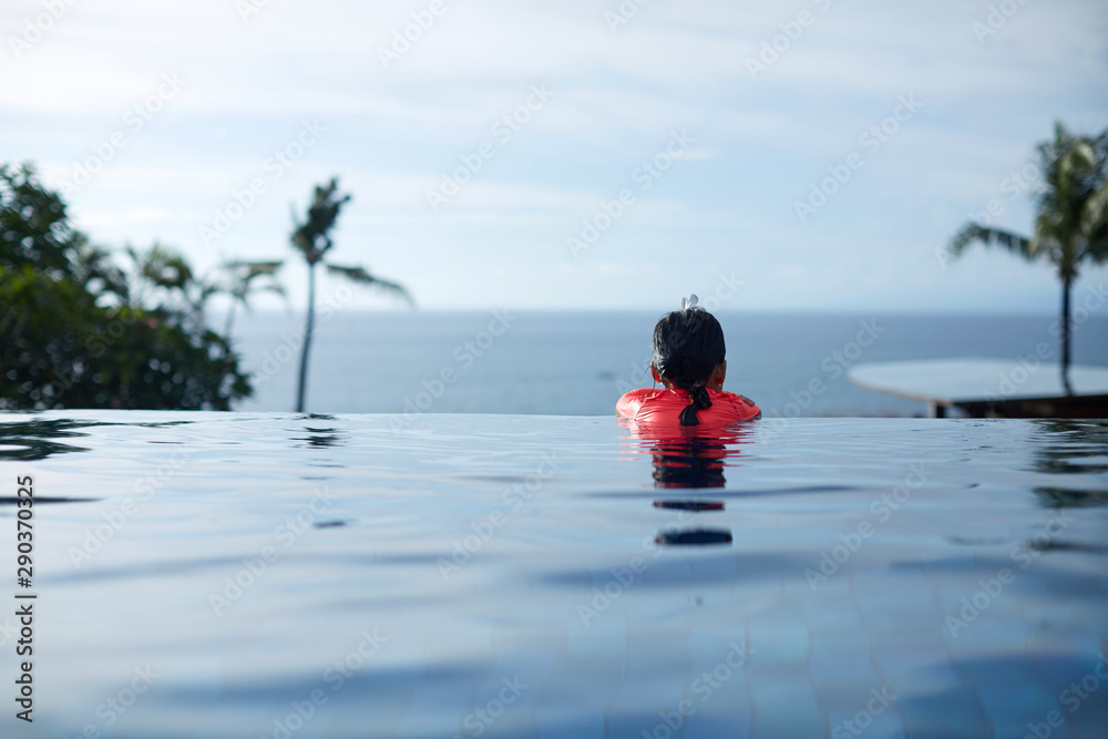 Cute Asian little girl looking into the distance in a swimming pool ...