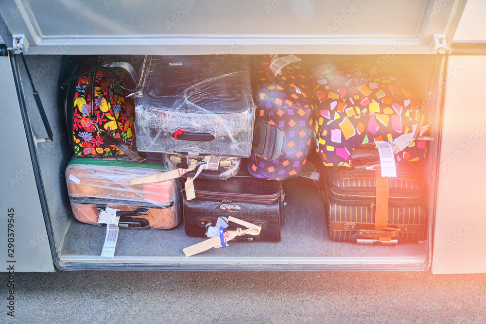 Suitcases stacked in the luggage compartment of a bus. Red and black ...