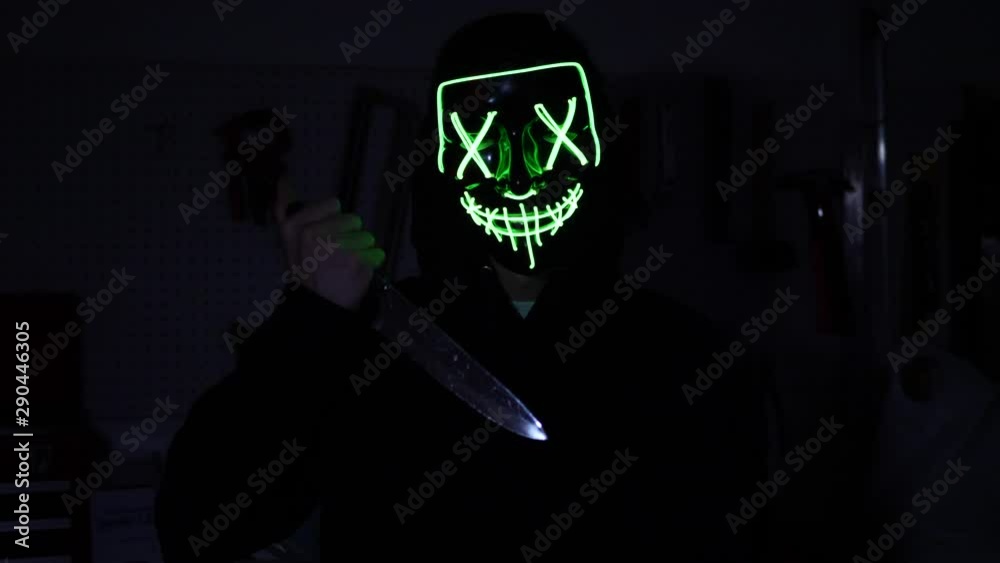 A terrifying slasher killer in a scary horror halloween mask pulling a ...